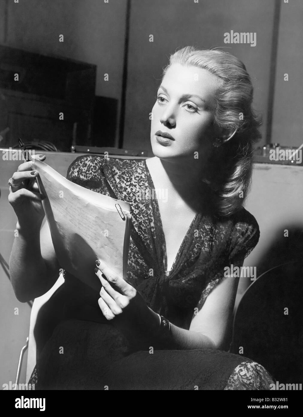 Young woman with pen in hand, reading a letter Stock Photo - Alamy