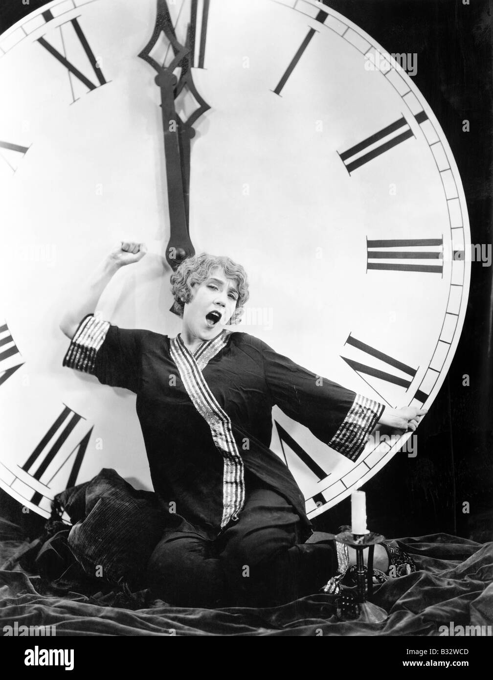 A young woman stretching in front of a giant clock striking midnight ...