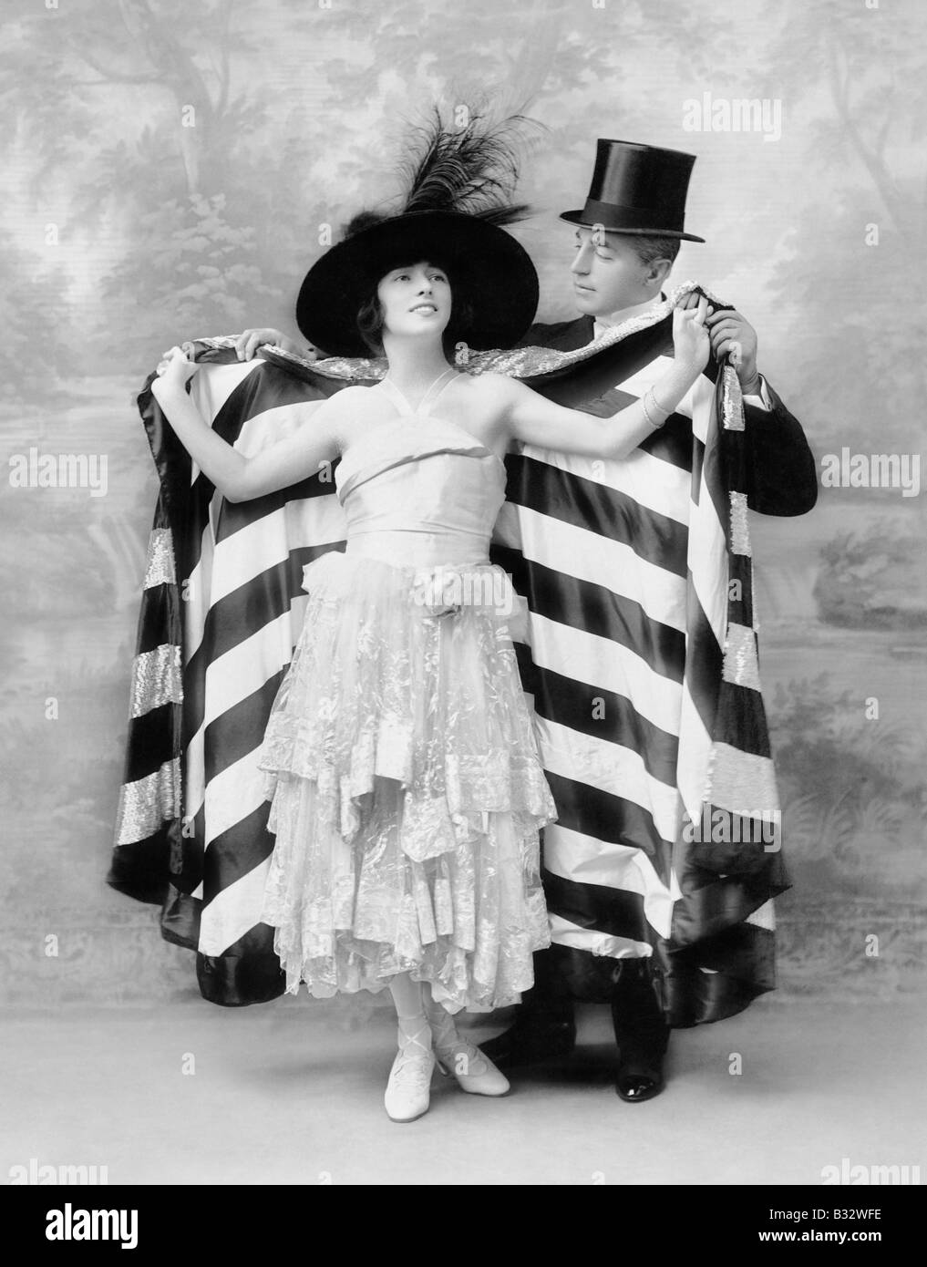 Man in a top hat helping a woman into a cape Stock Photo - Alamy