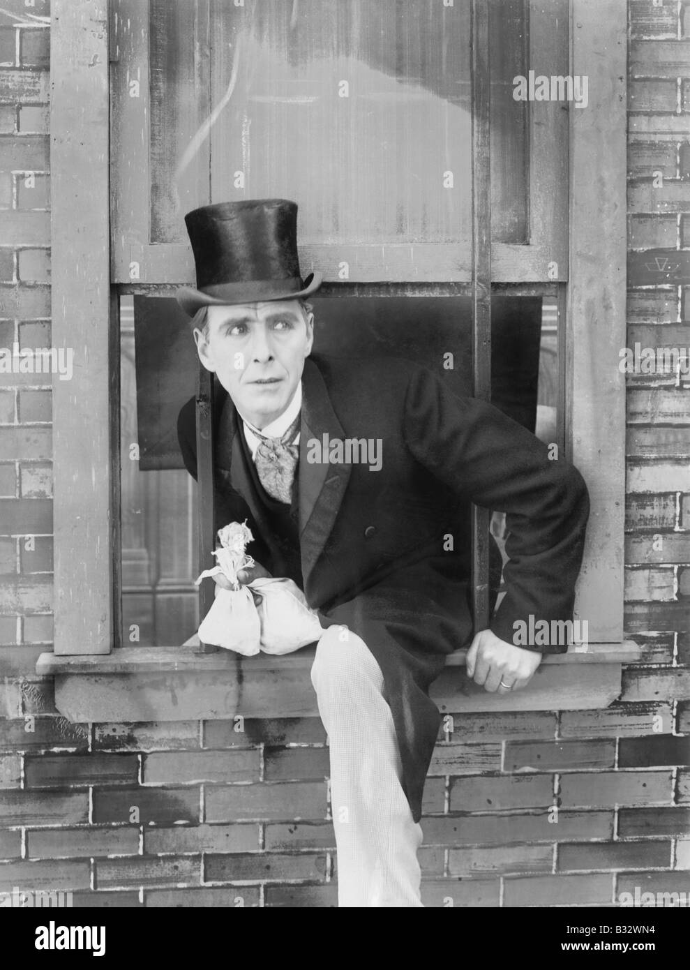 Banker with bags of money escaping through a window Stock Photo - Alamy