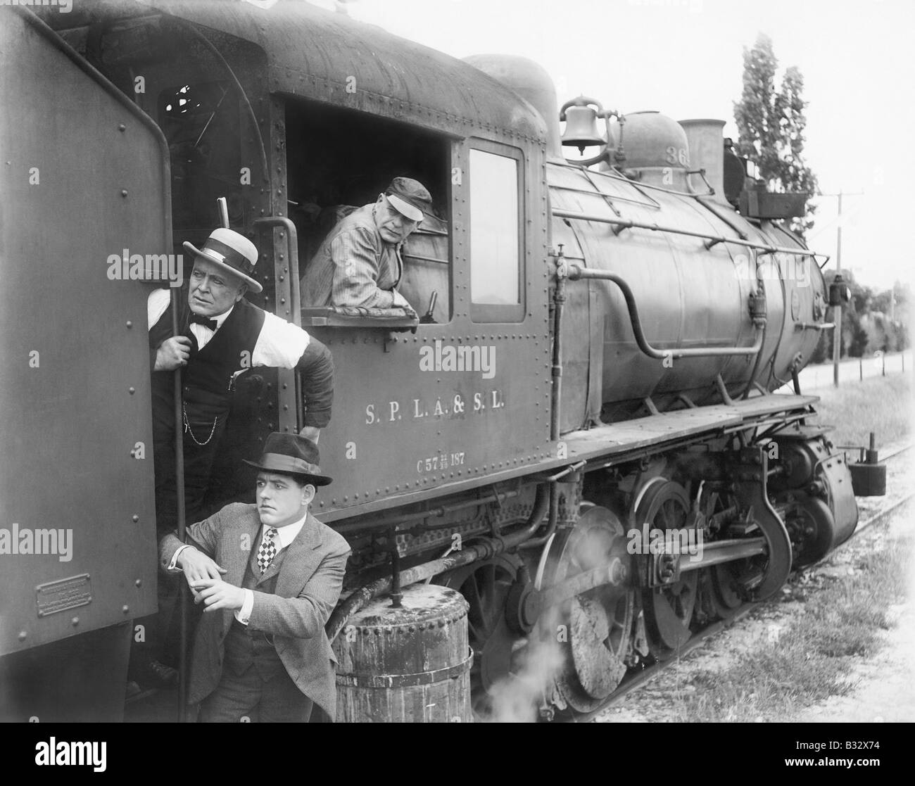 Three men waiting at a steam locomotive Stock Photo - Alamy