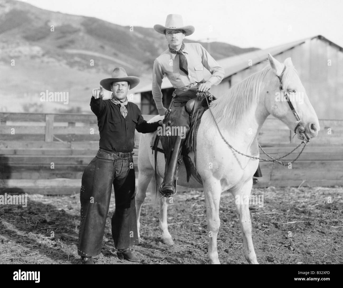 Two cowboys and a white horse Stock Photo - Alamy