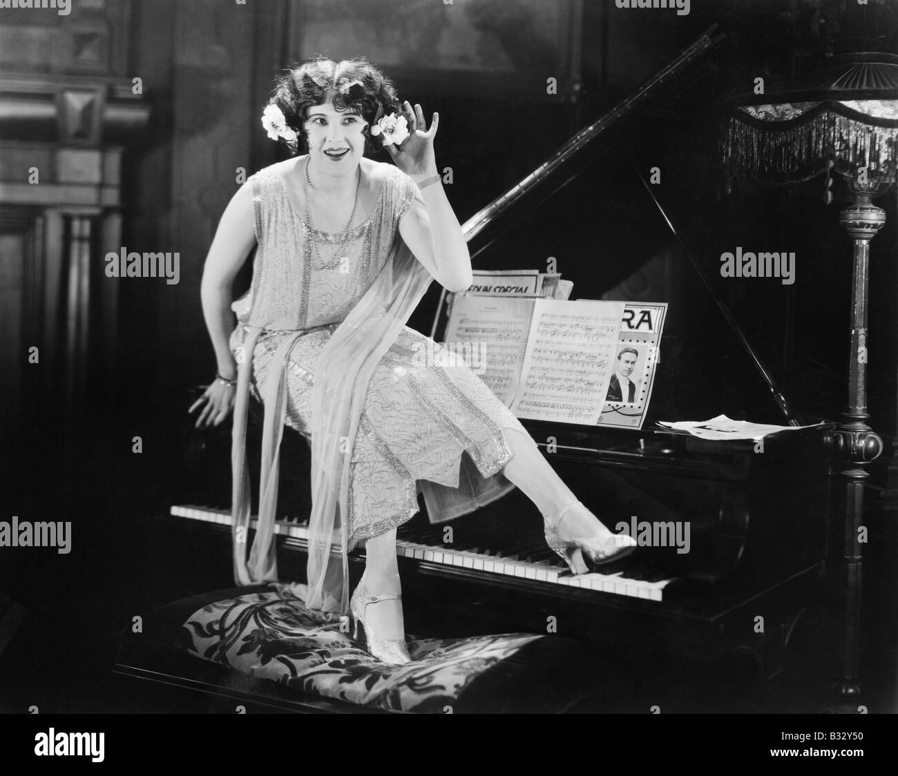 Woman sitting on top of a grand piano Stock Photo - Alamy
