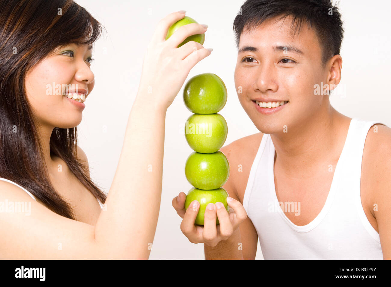 A healthy looking couple make a tower from green apples Stock Photo - Alamy