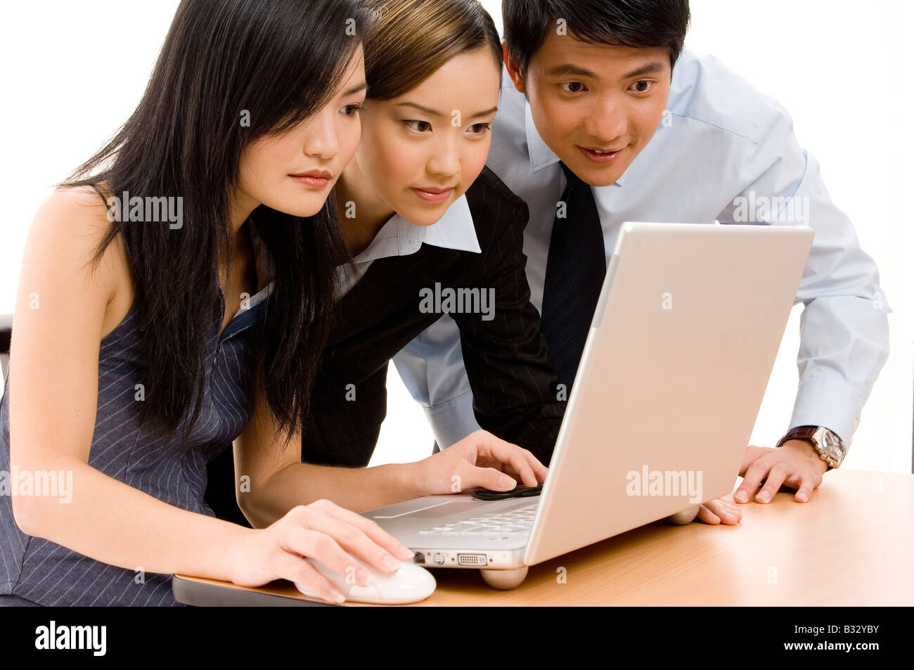 Three business people looking at a laptop computer Stock Photo - Alamy