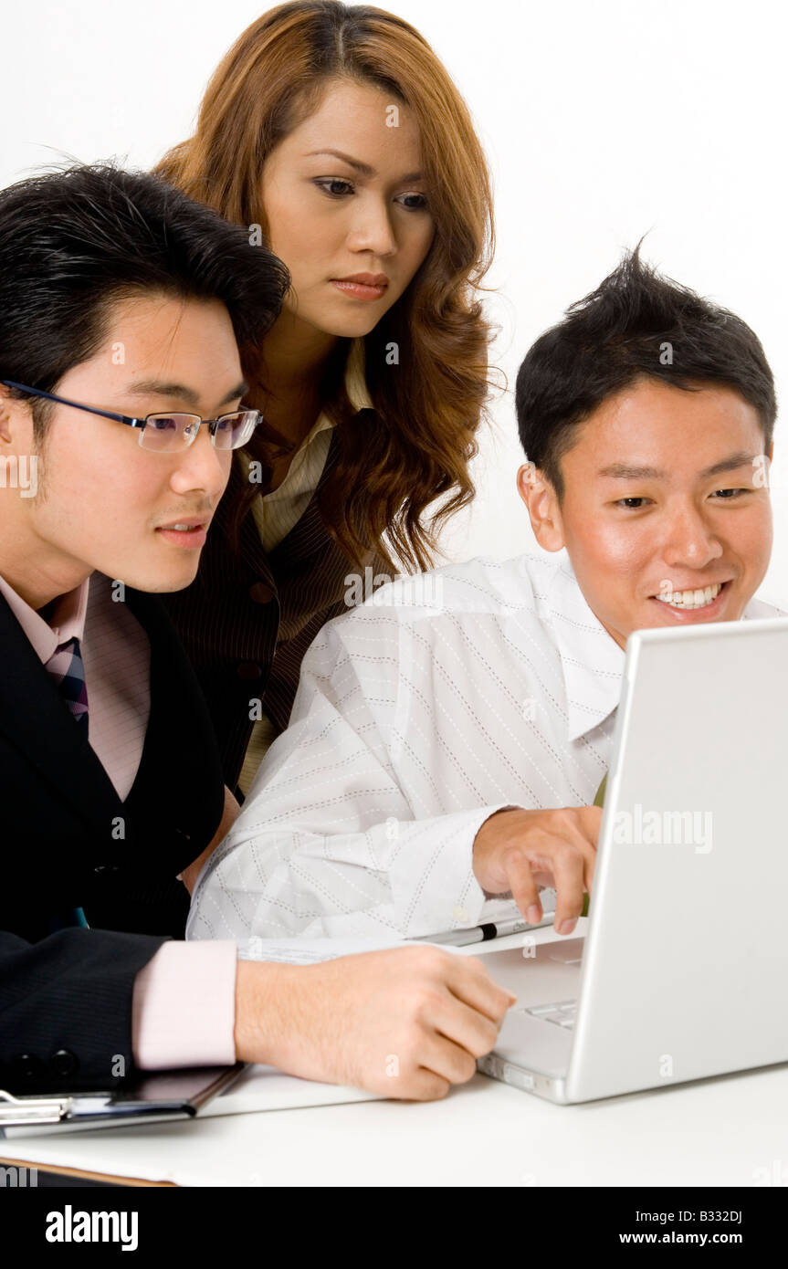 Three asian business people looking at a laptop computer Stock Photo ...