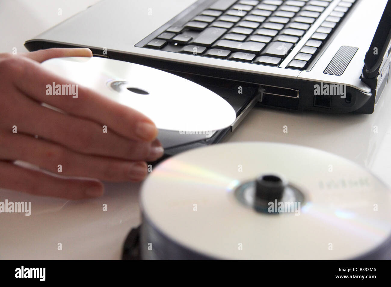 a hand, a laptop and some discs Stock Photo - Alamy