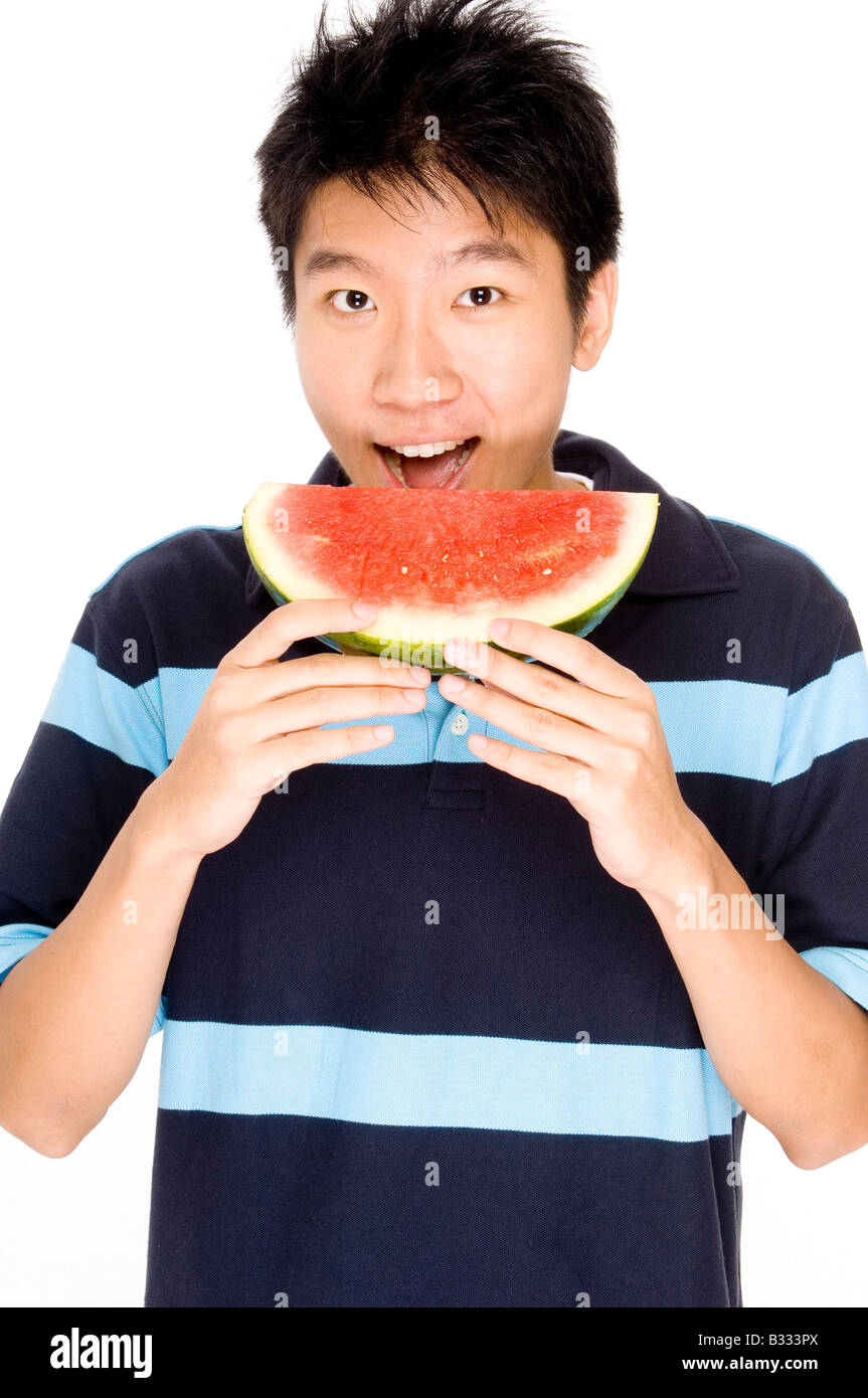 A young chinese man eating a slice of melon Stock Photo - Alamy