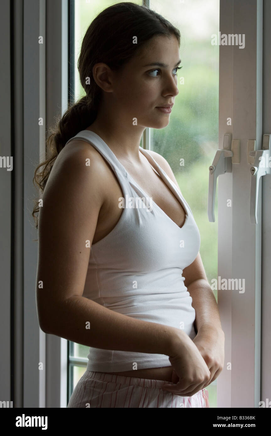 A beautiful young woman looks out of a window Stock Photo - Alamy