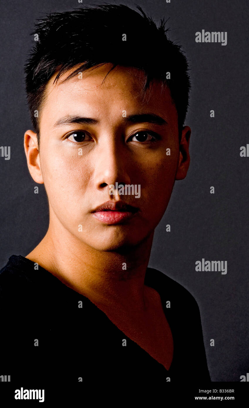 A portrait of an asian male model in black on a grey background Stock ...