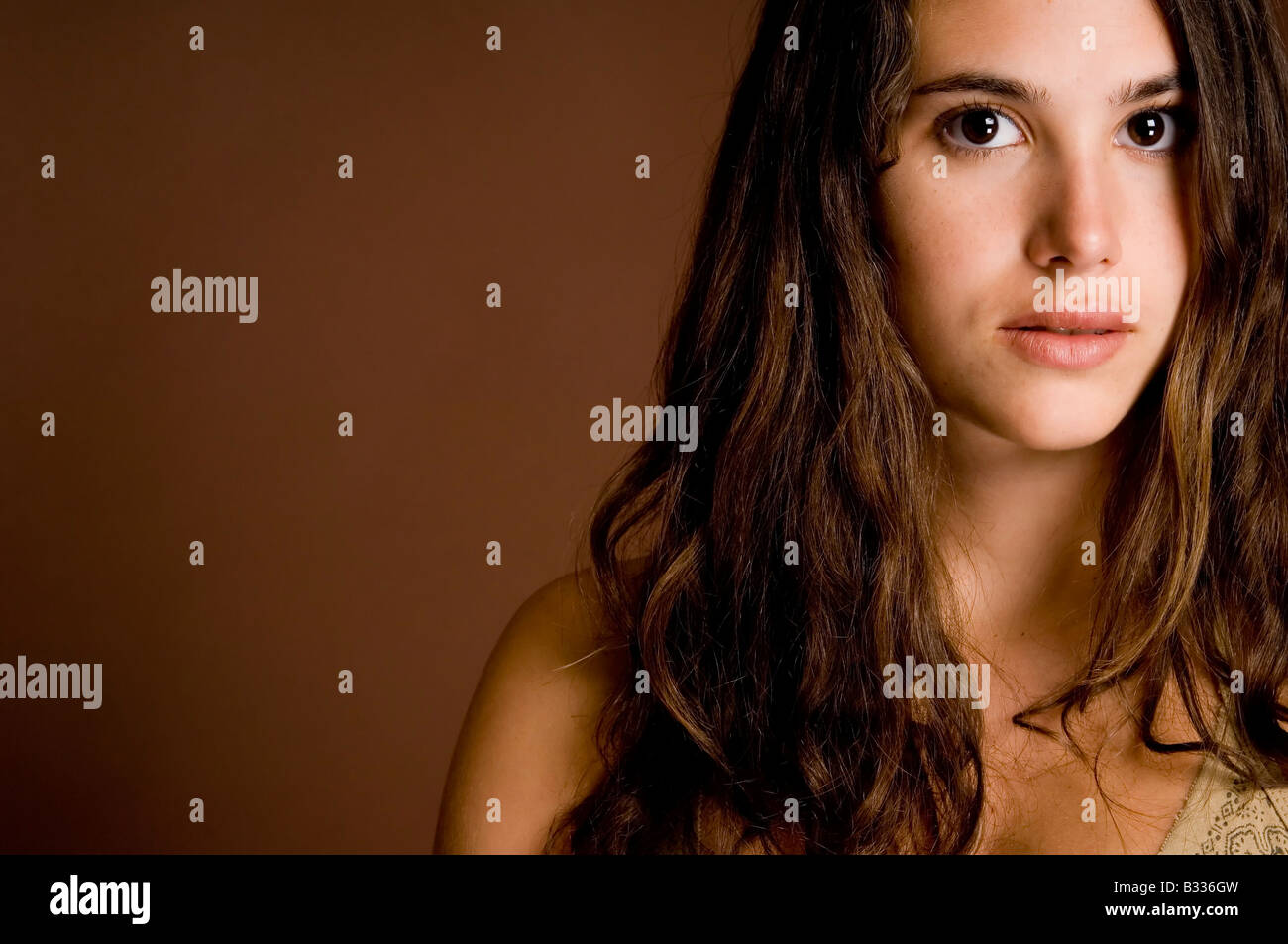 A beautiful demure young woman on a brown backdrop Stock Photo - Alamy