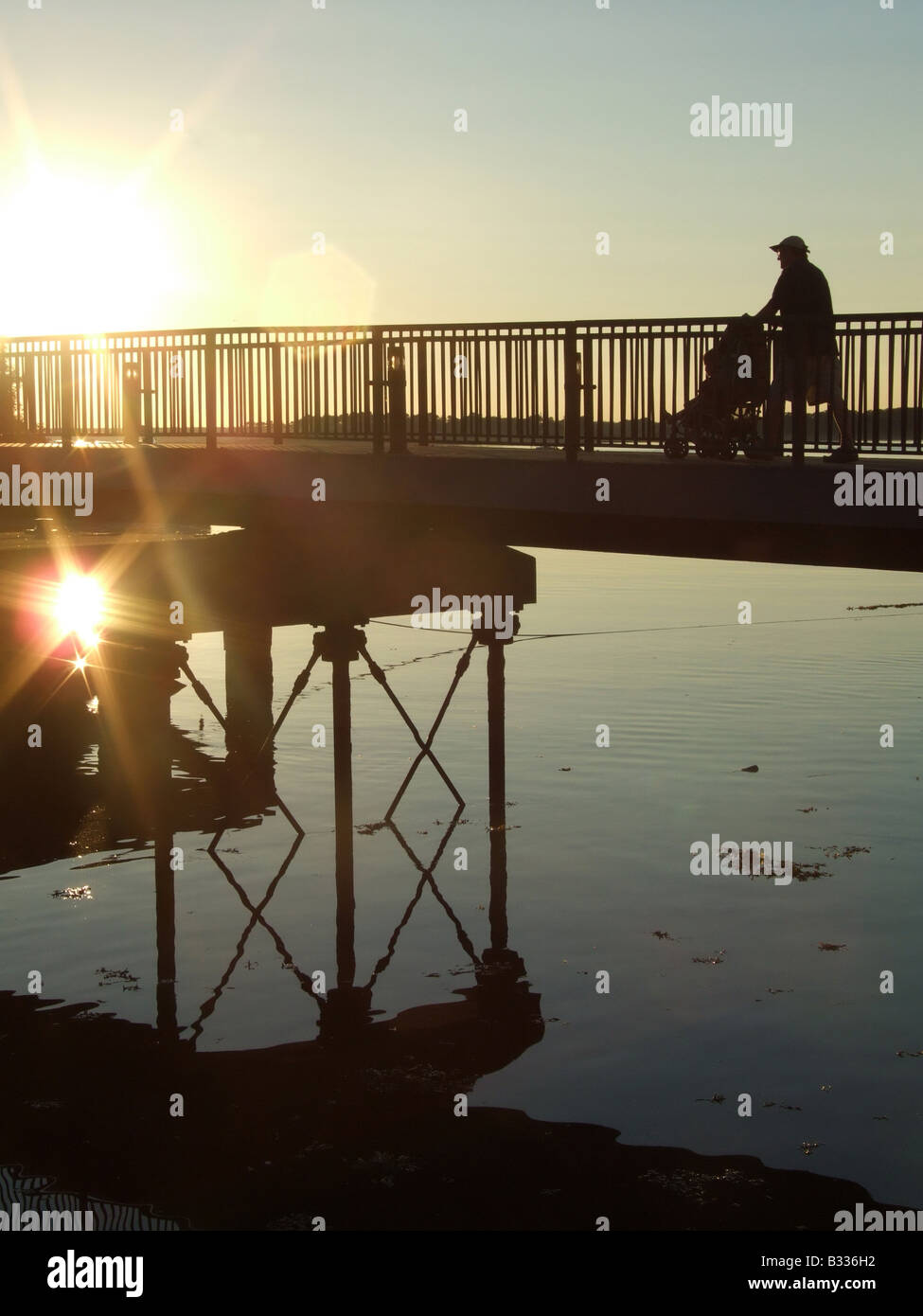 moody scene of people crossing bridge at sunset Stock Photo - Alamy