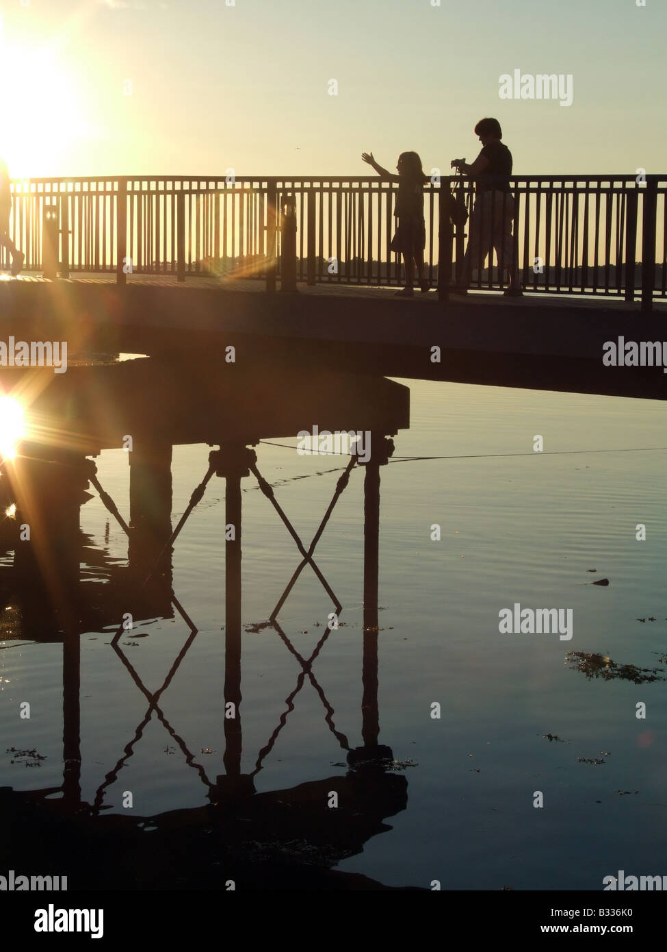 moody scene of people crossing bridge at sunset Stock Photo - Alamy
