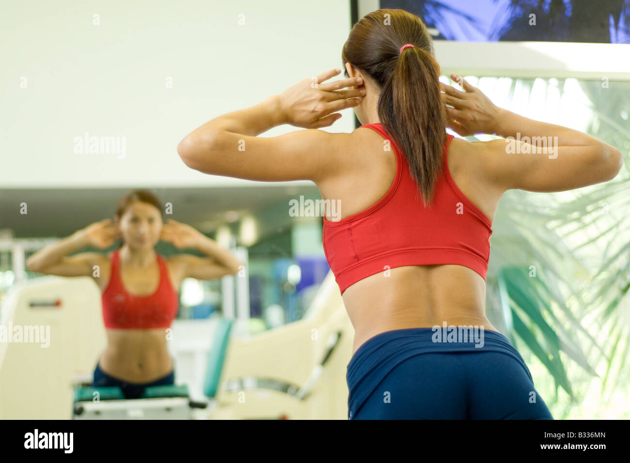 A woman works out at a gym looking at her reflection Stock Photo - Alamy