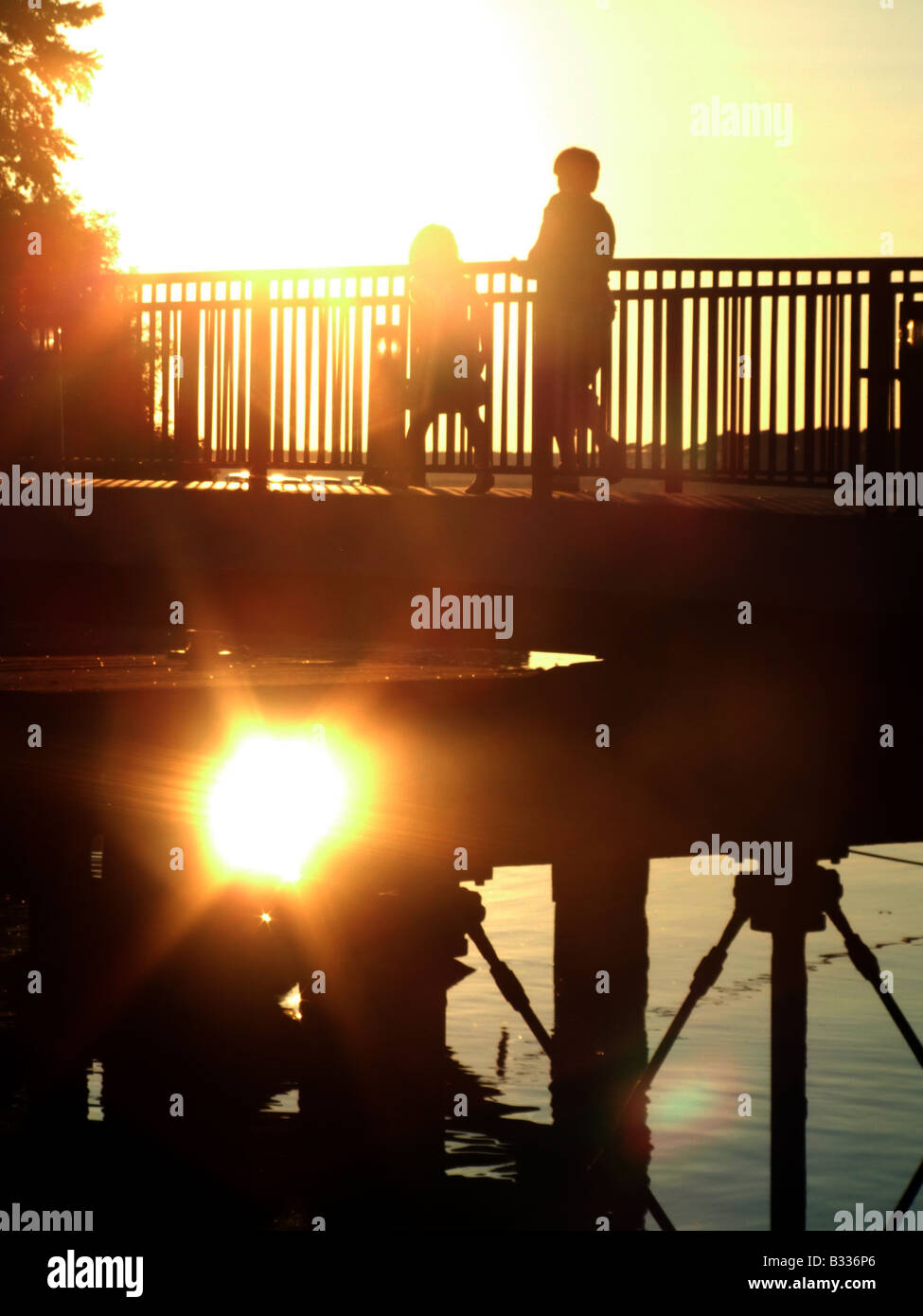 moody scene of people crossing bridge at sunset Stock Photo - Alamy