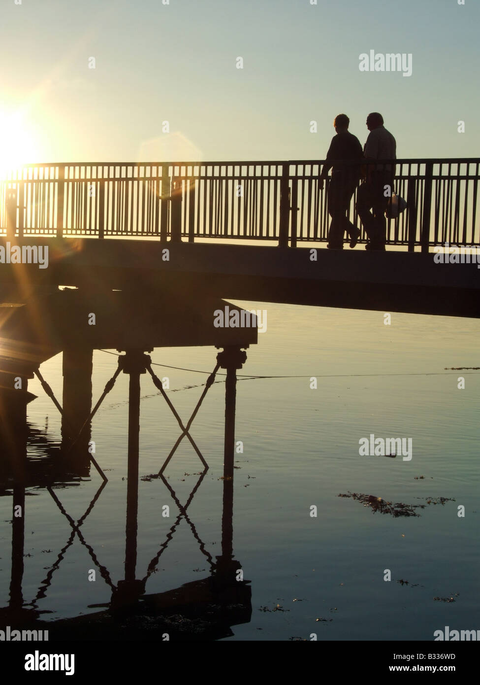moody scene of people crossing bridge at sunset Stock Photo - Alamy