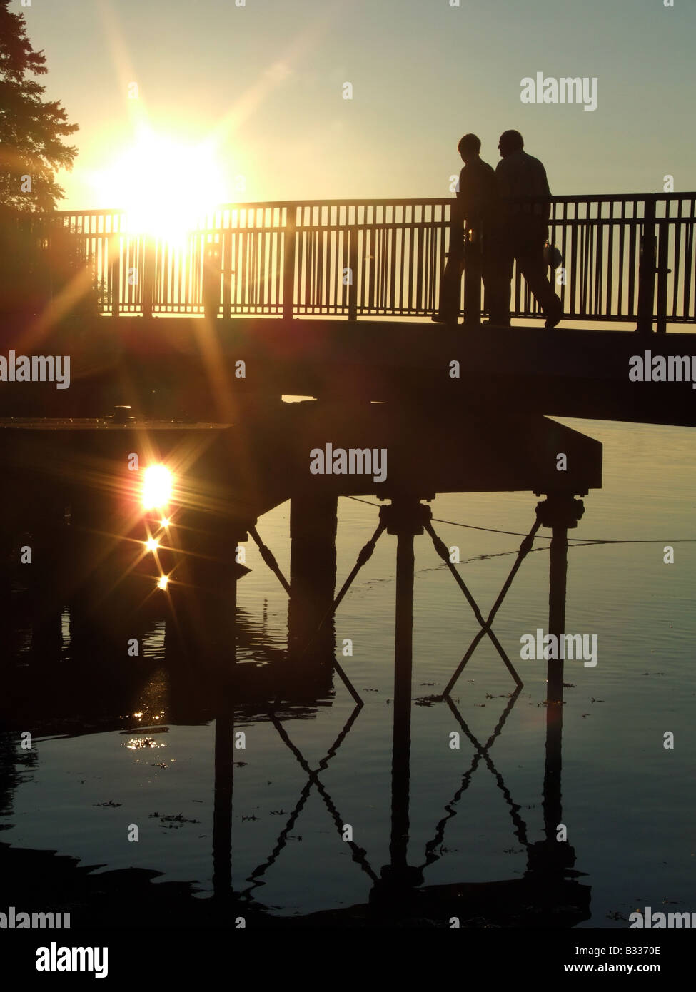 moody scene of people crossing bridge at sunset Stock Photo - Alamy