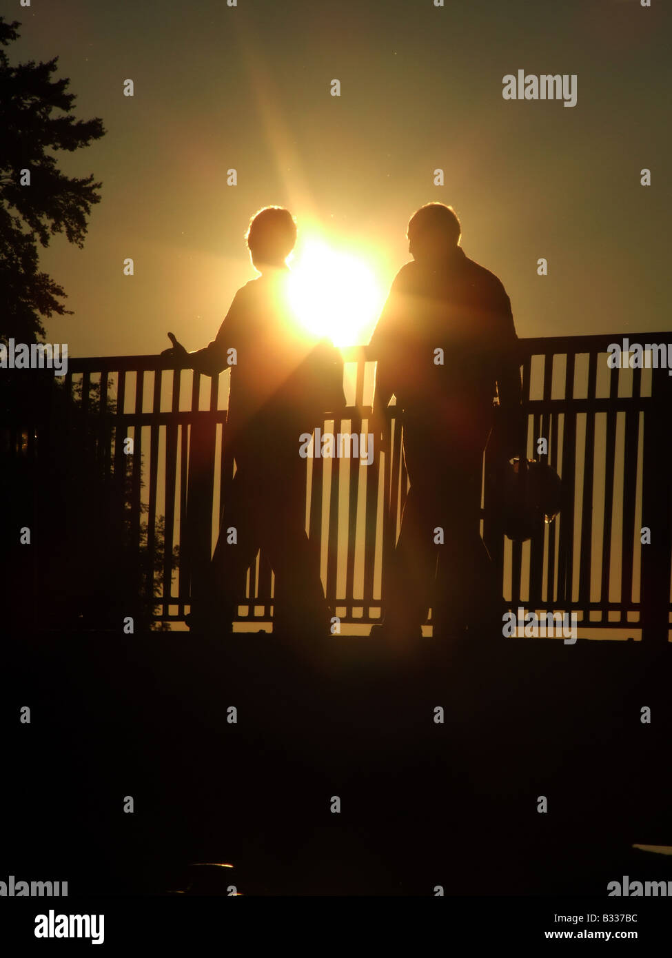 moody scene of people crossing bridge at sunset Stock Photo - Alamy