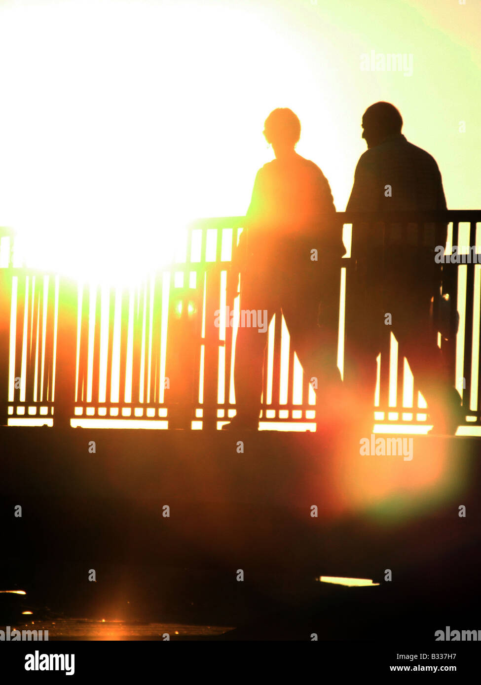 moody scene of people crossing bridge at sunset Stock Photo - Alamy