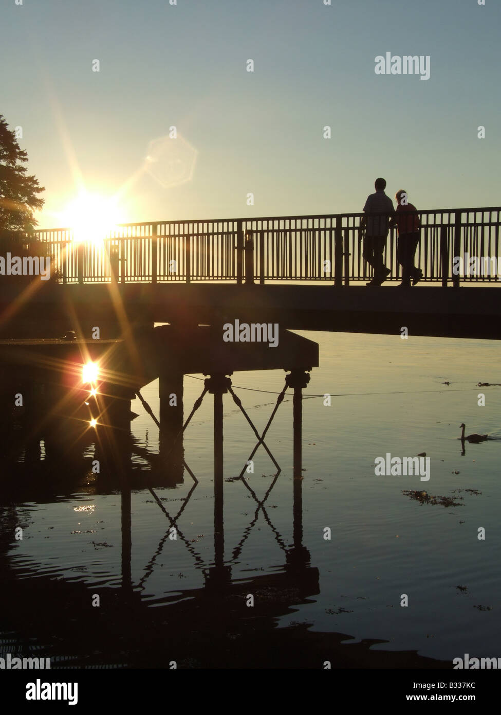 moody scene of people crossing bridge at sunset Stock Photo - Alamy