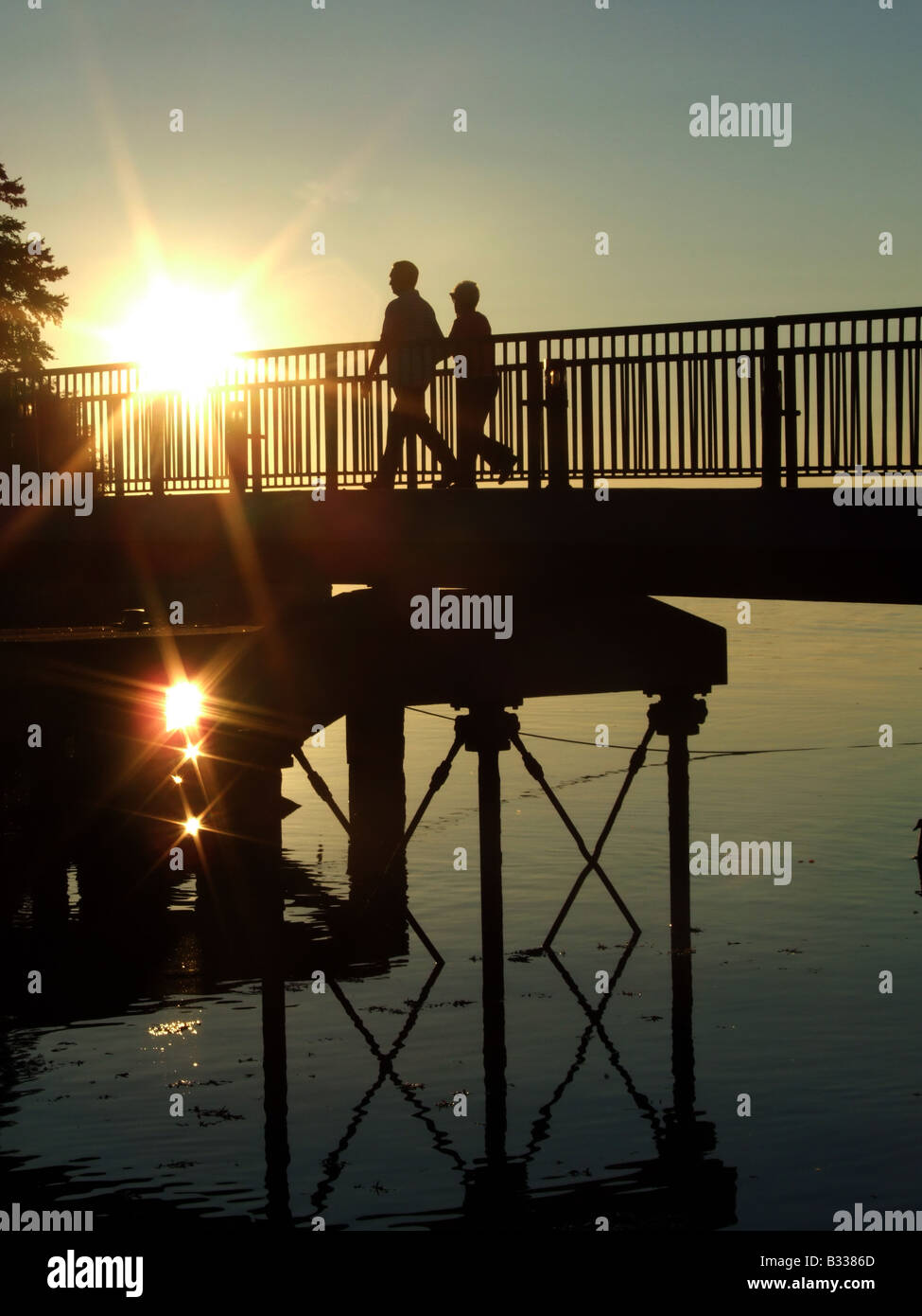 moody scene of people crossing bridge at sunset Stock Photo - Alamy