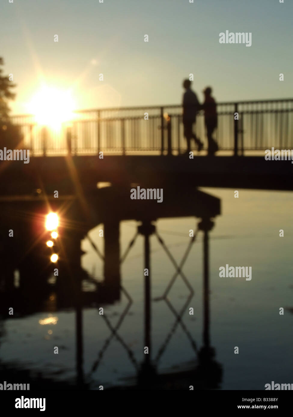 moody scene of people crossing bridge at sunset Stock Photo - Alamy