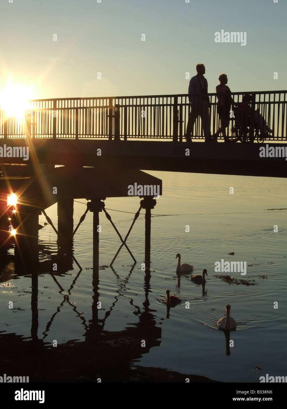 moody scene of people crossing bridge at sunset Stock Photo - Alamy