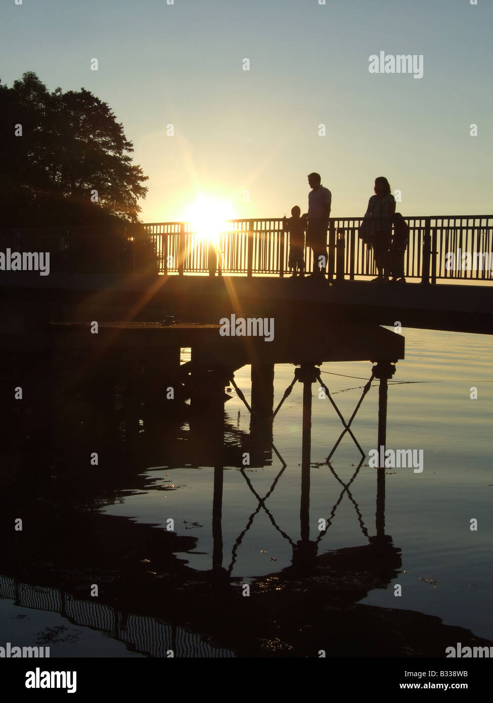 moody scene of family crossing bridge at sunset Stock Photo - Alamy