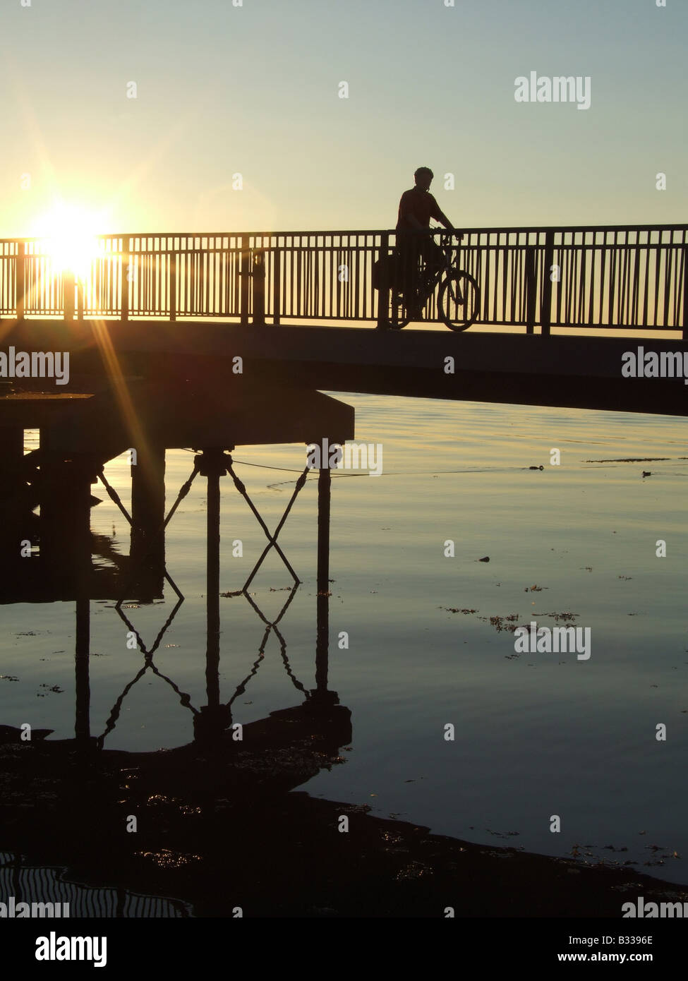 moody scene of person crossing bridge at sunset Stock Photo - Alamy
