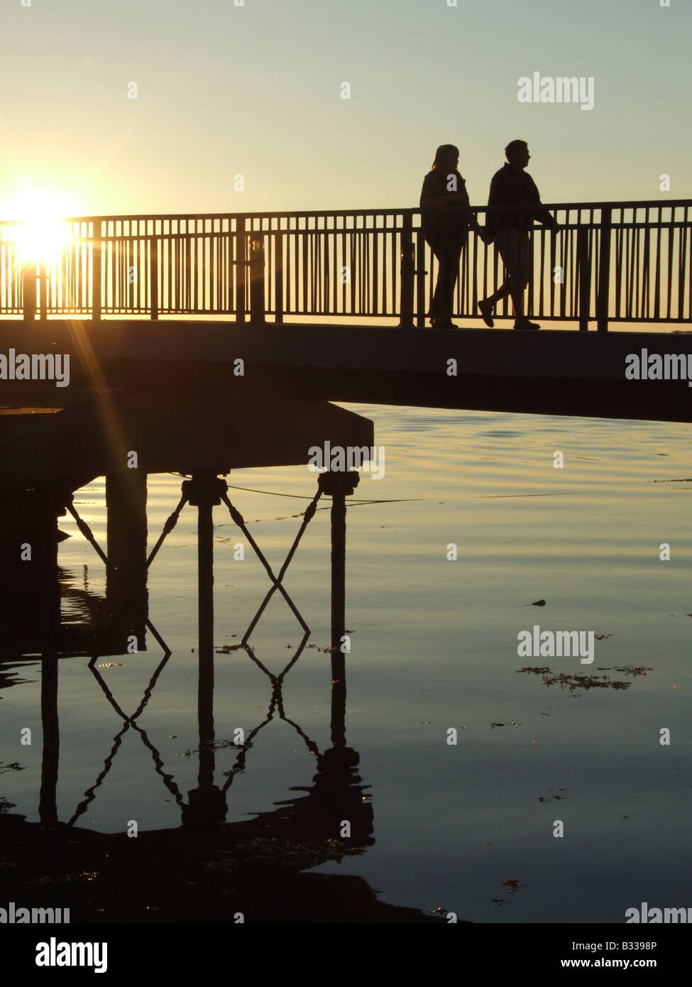 moody scene of people crossing bridge at sunset Stock Photo - Alamy