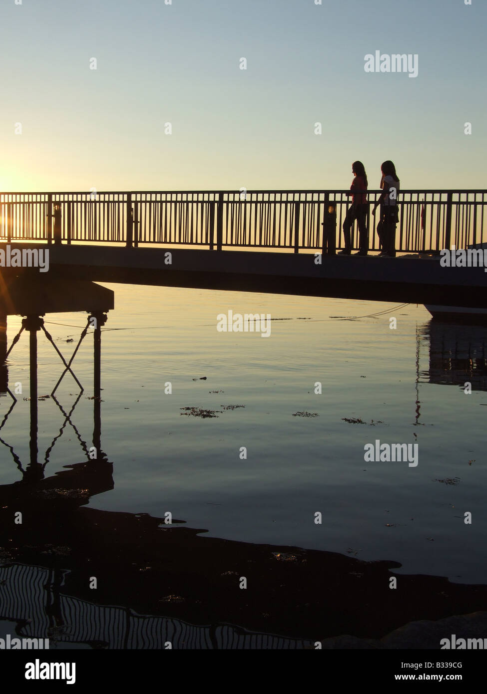 moody scene of person crossing bridge at sunset Stock Photo - Alamy