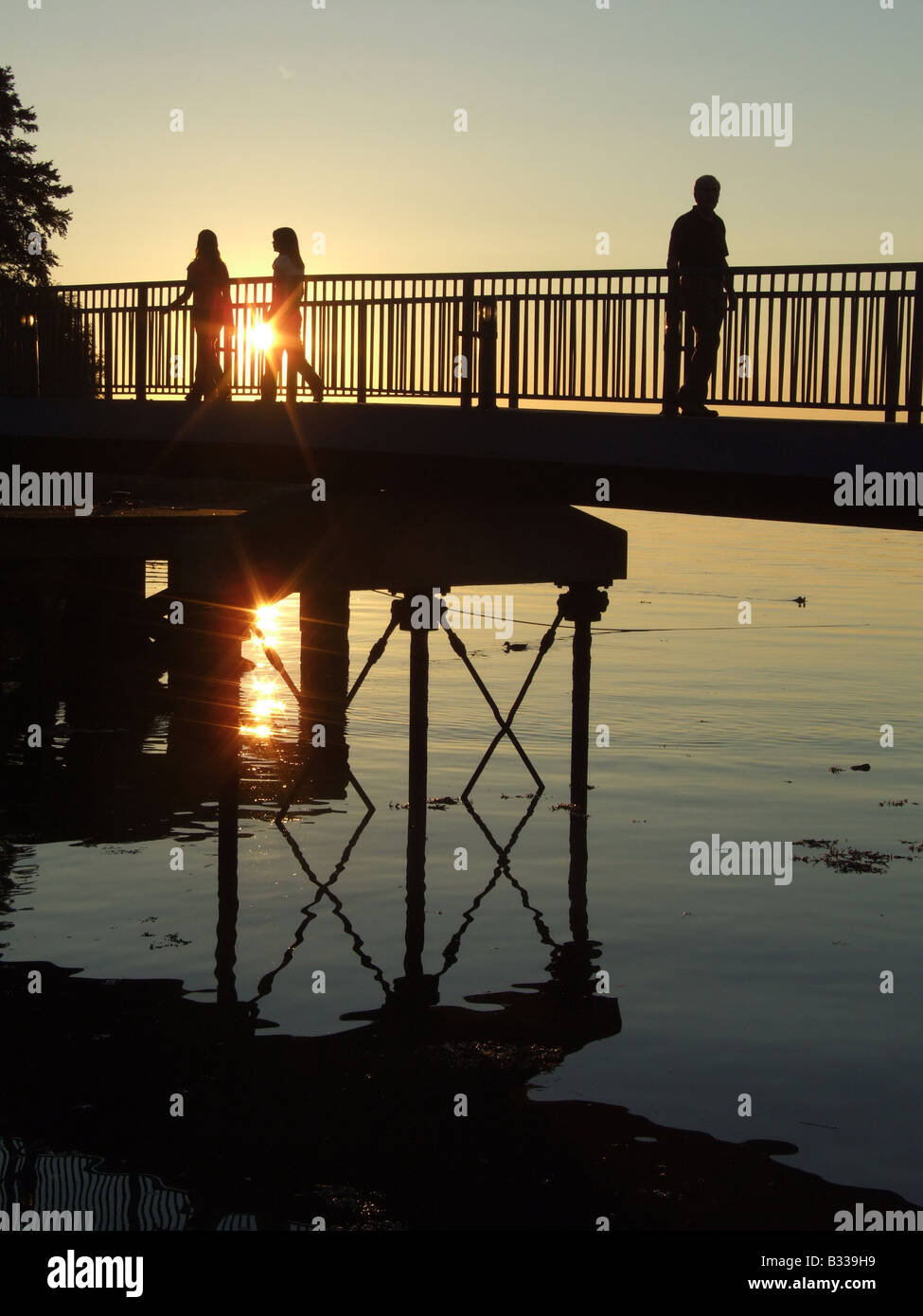 moody scene of people crossing bridge at sunset Stock Photo - Alamy