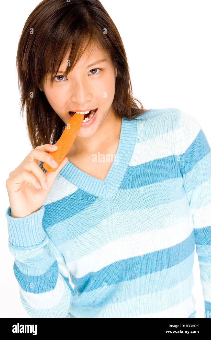 A cute young asian woman biting on a carrot Stock Photo - Alamy
