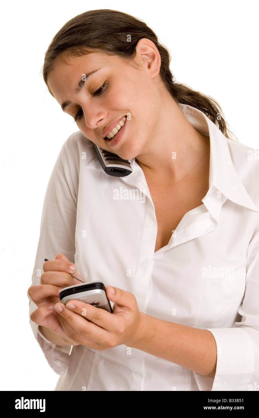 An attractive young woman makes notes on her PDA whilst on the phone ...