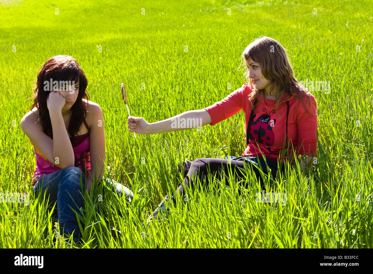 Blond young woman offering candy to her friend Stock Photo - Alamy