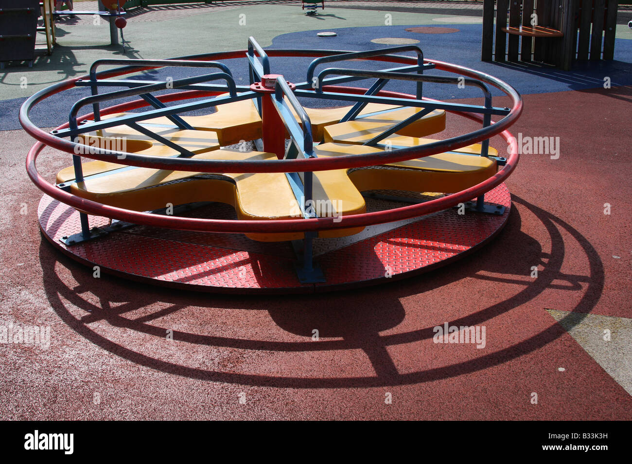 Partly damaged roundabout in childrens playground with rubberised floor ...