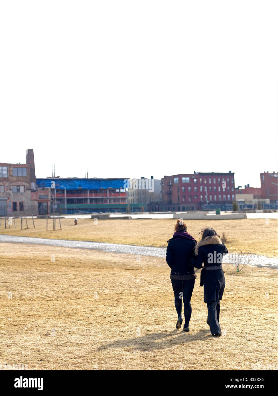 Two women walk through a field towards an urban neighborhood Stock ...