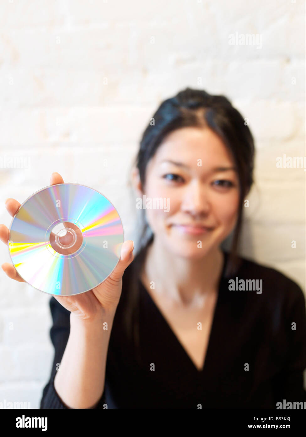 A close up view of a smiling young Asian woman holding up a CD Stock ...