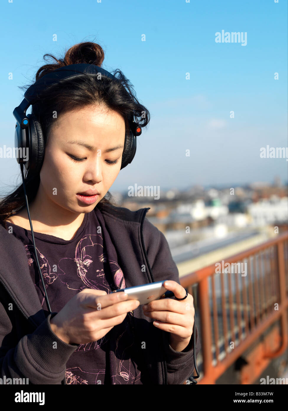 A young woman listening to music on her mobile phone Stock Photo - Alamy