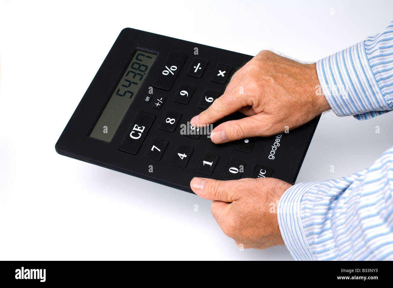 A businessman's hand doing calculations on an oversized calculator ...