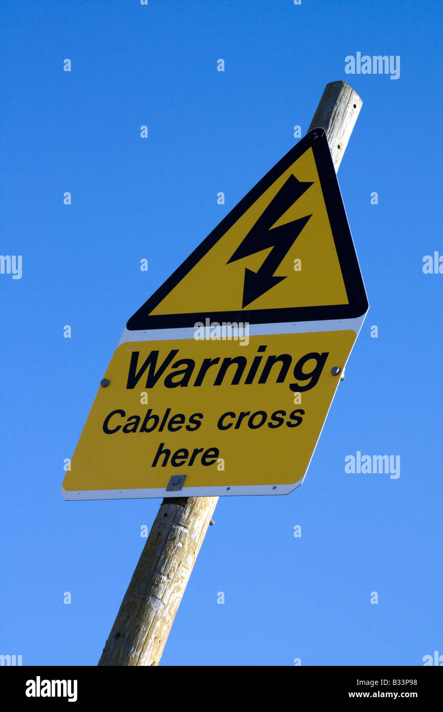 warning sign post cables cross here Stock Photo - Alamy