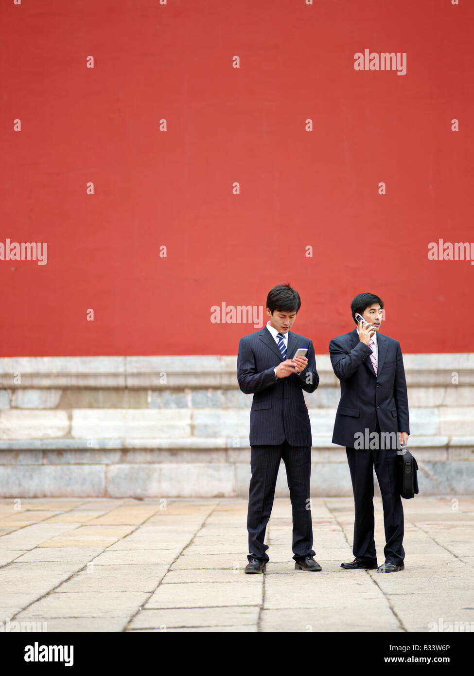 Two Chinese businessmen in suits having a discussions on the phone in ...