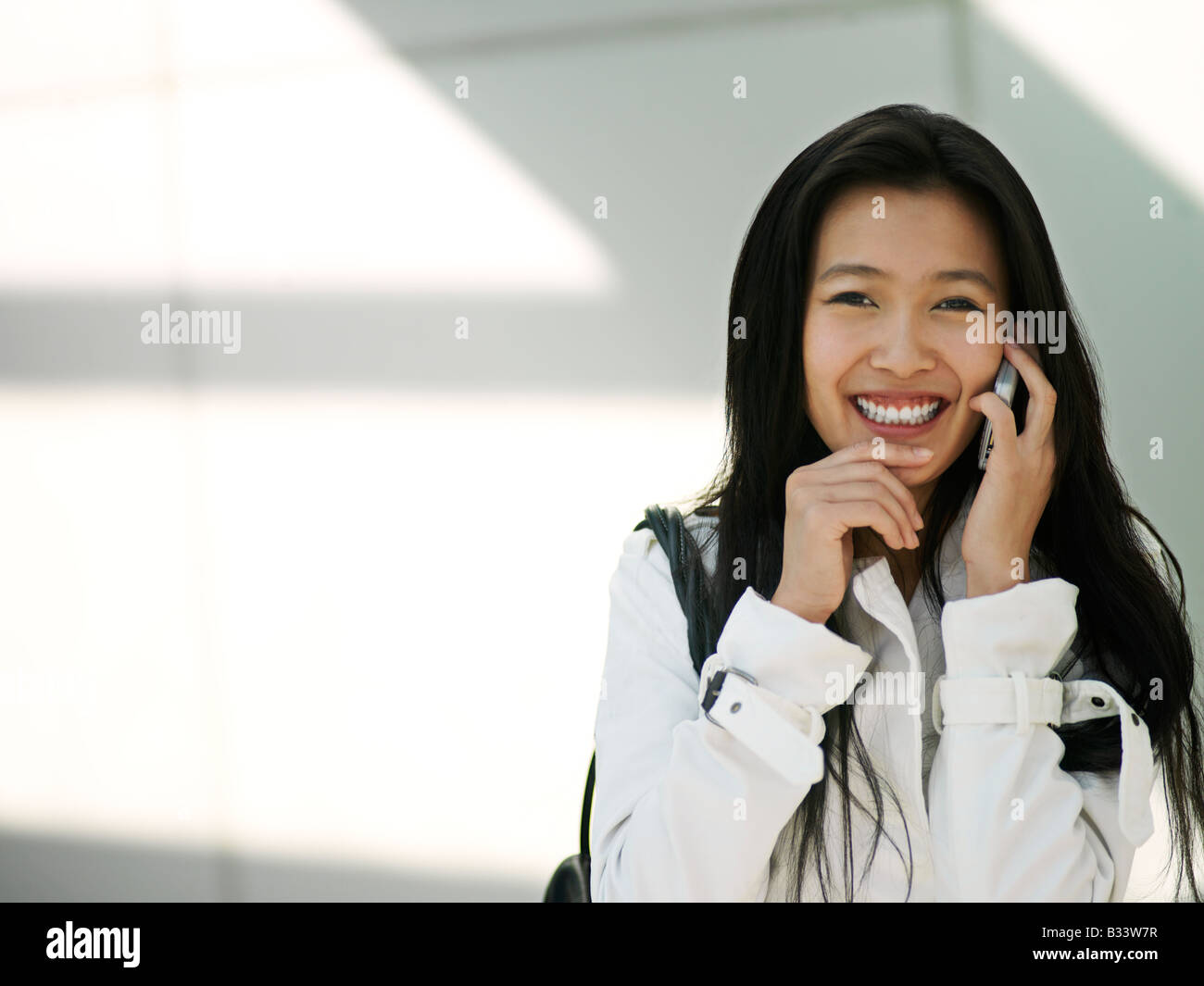 A young Chinese business woman using her mobile phone PDA in the city ...