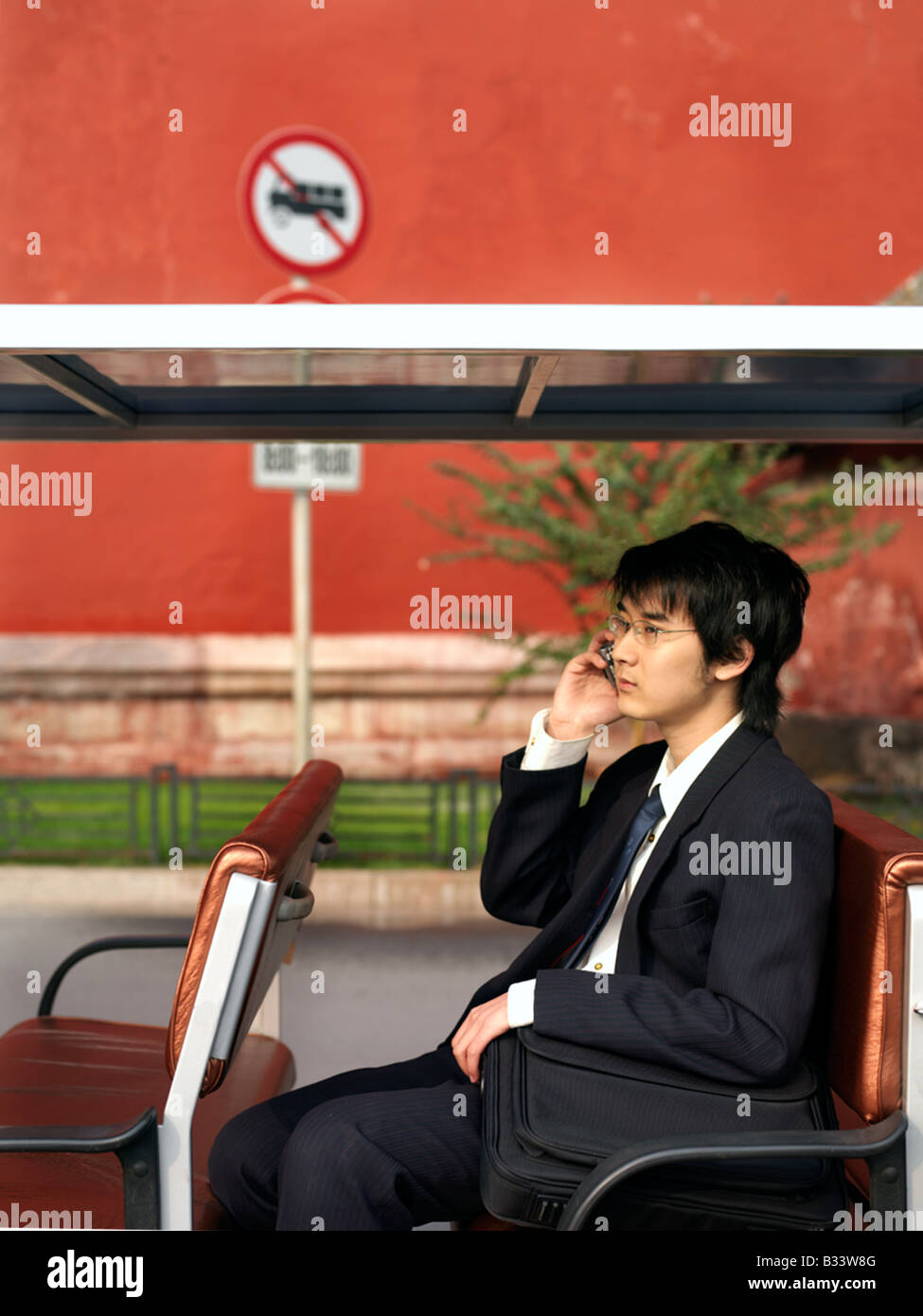 young Chinese man using his portable phone to communicate and perform ...