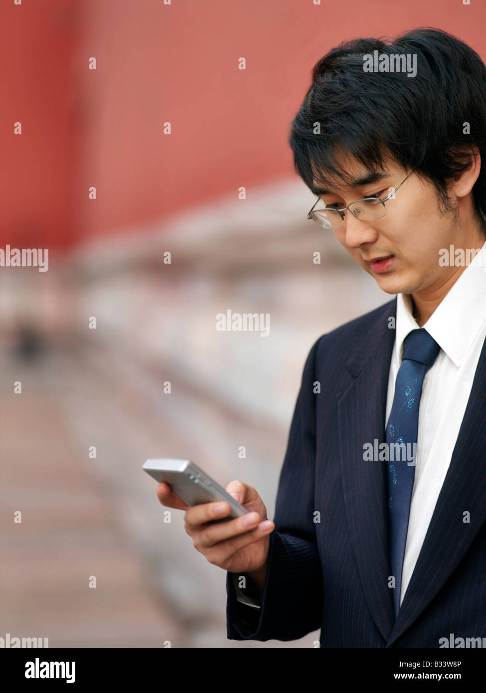 young Chinese man using his portable phone to communicate and perform ...