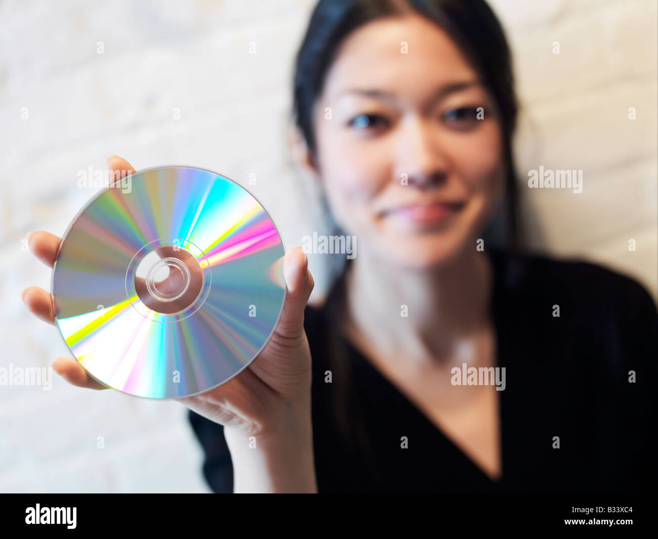 A close up view of a smiling young Asian woman holding up a CD Stock ...