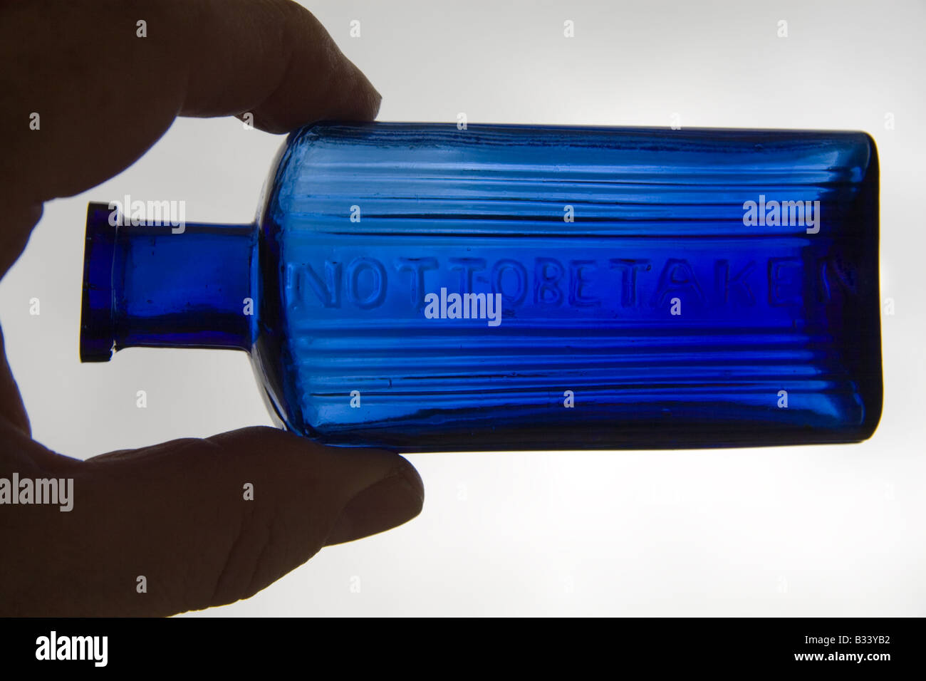 A hand held blue antique glass bottle inscribed "Not to be Taken Stock ...