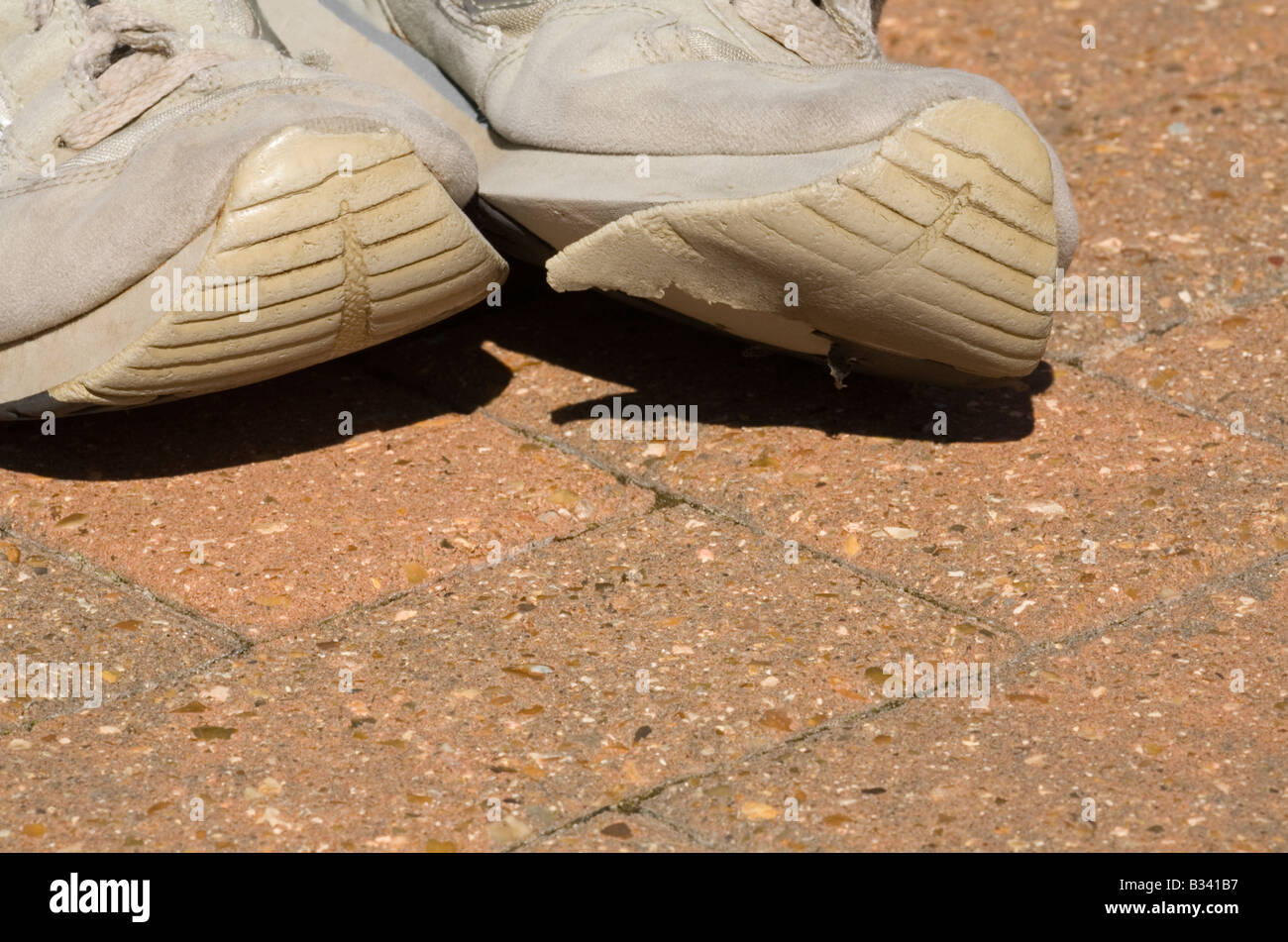 A pair of old worn out training shoes on a patio Stock Photo - Alamy