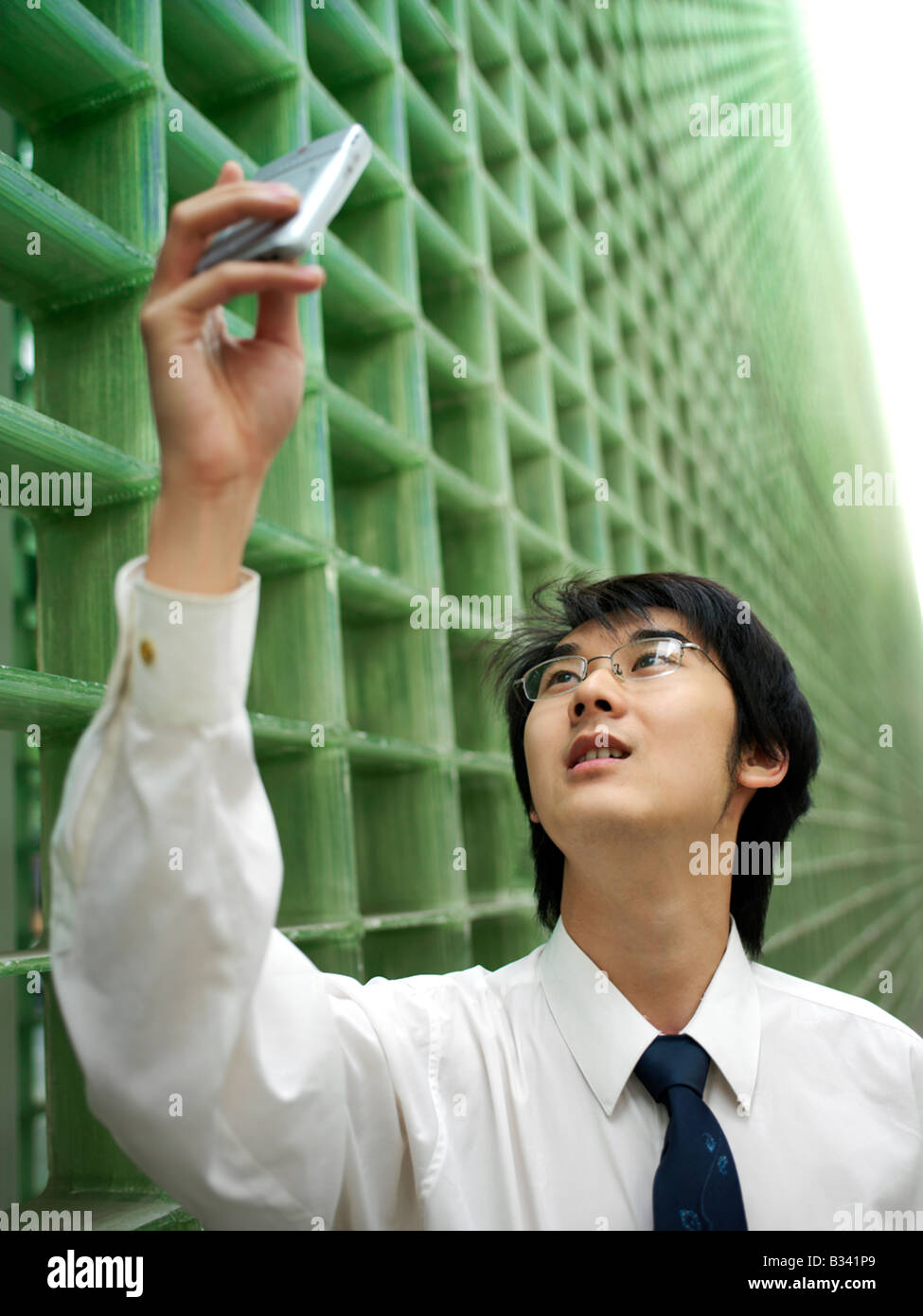Young Chinese man using his portable phone to communicate and take ...