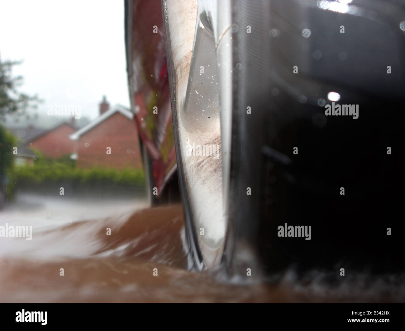 rain and river overflow flooding a street past car tyre and alloy wheel ...